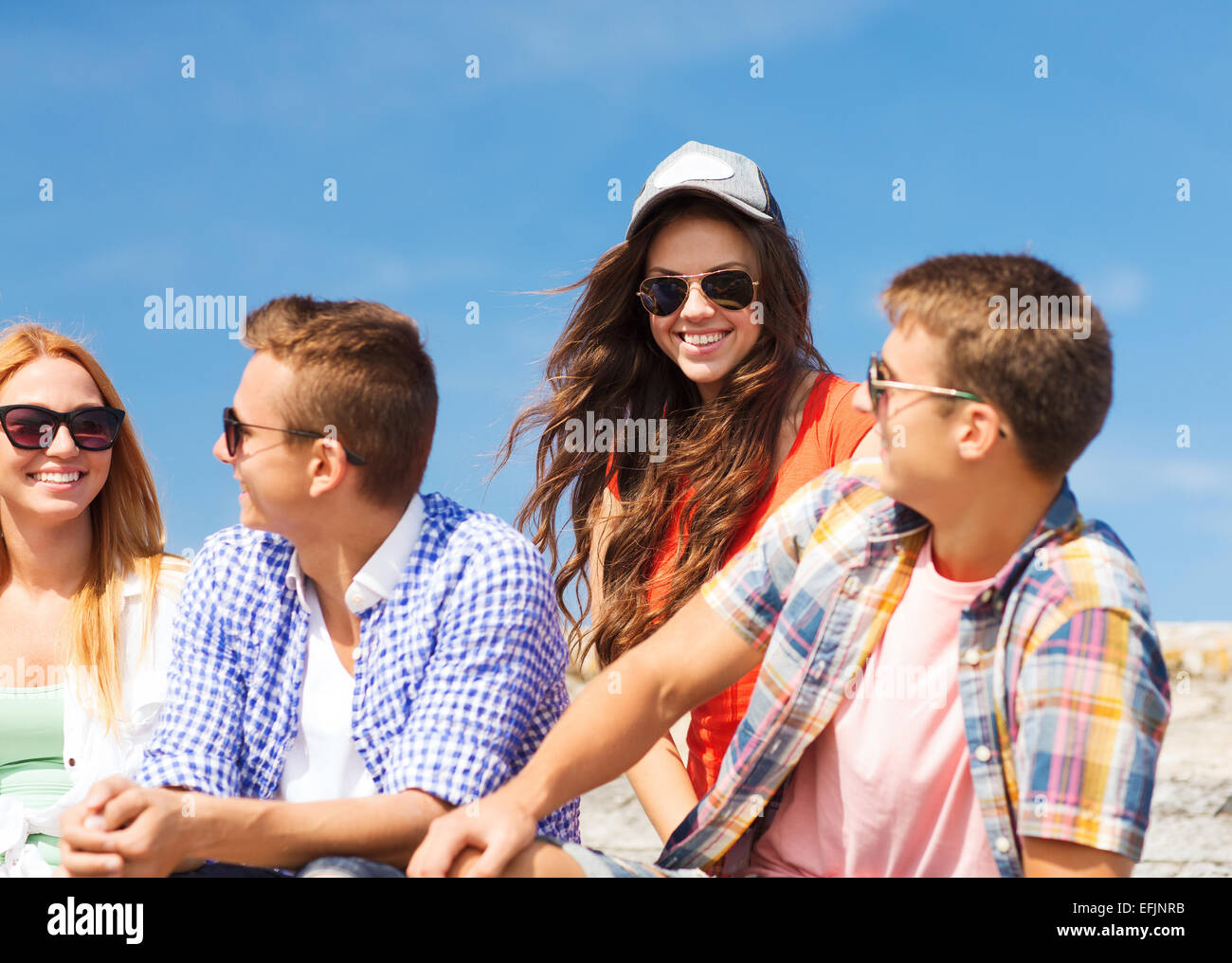 group of smiling friends sitting on city street Stock Photo - Alamy
