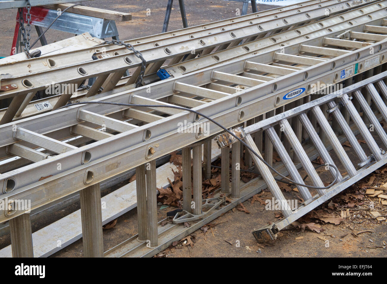 Stack of ladders chained together on ground at a construction site ...