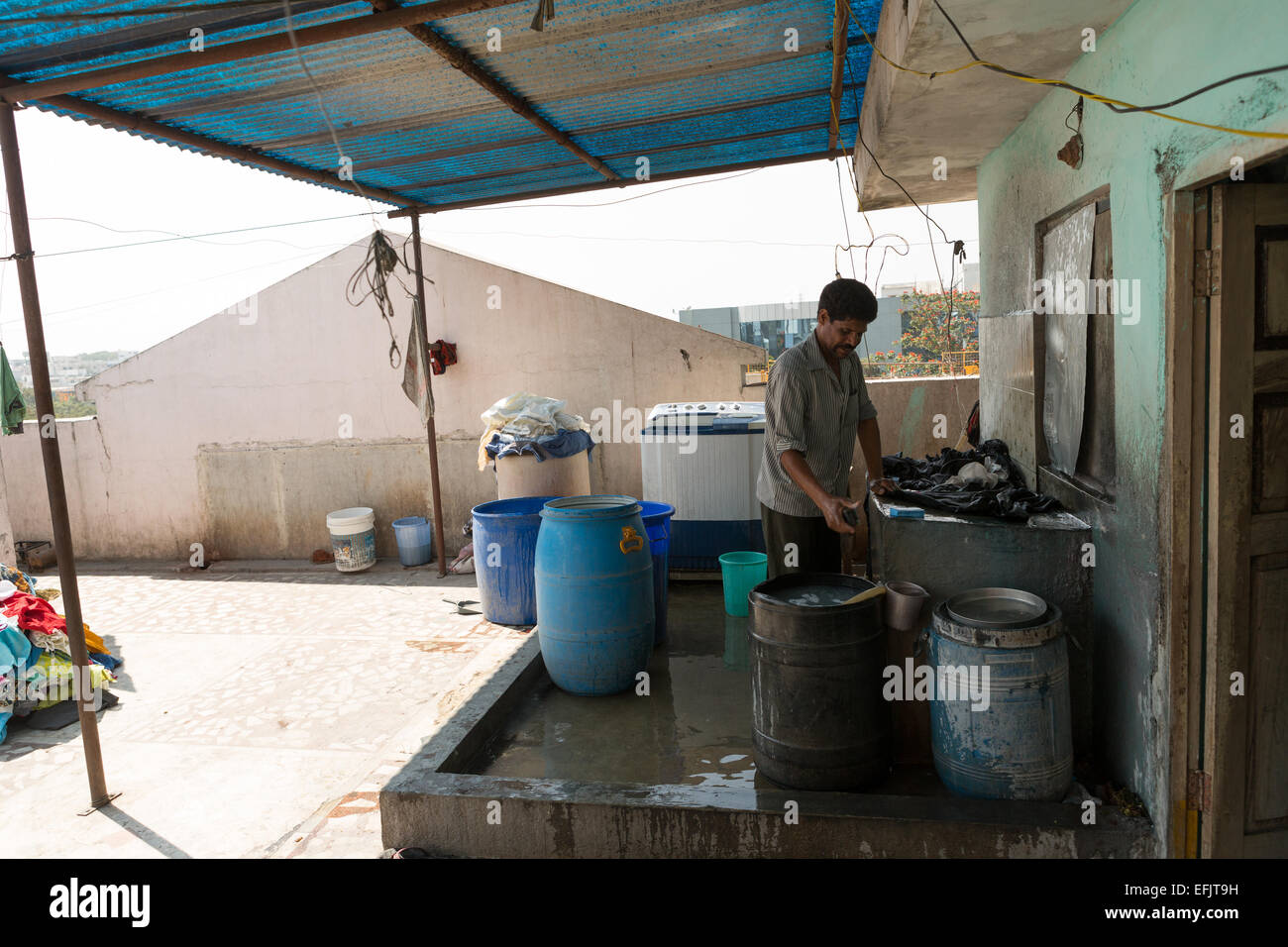 Indian man washing clothes on a rooftop Stock Photo - Alamy
