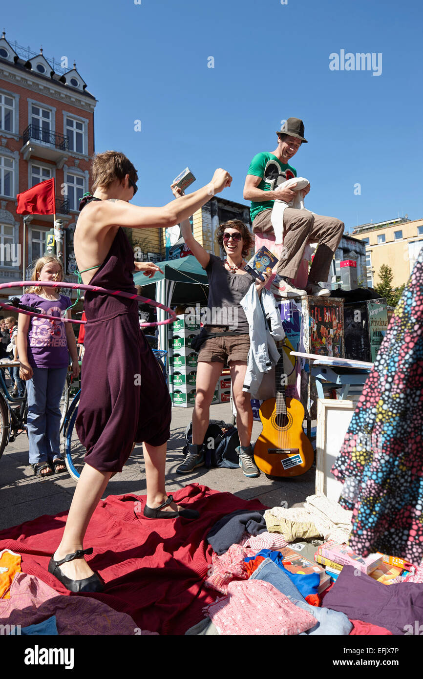 Musician playing music on top of a power box, woman hula hooping at her ...