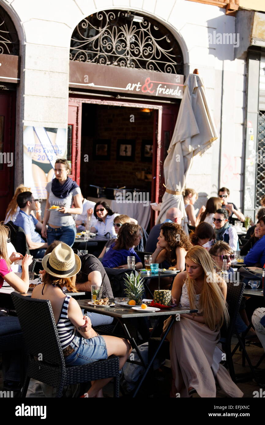 Young people sitting in front of a bar, Navigli quarter, Milan ...