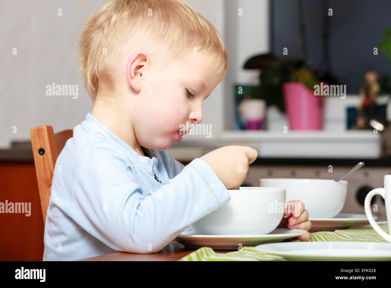 Happy childhood. Blond boy kid child eating corn flakes cereal with ...