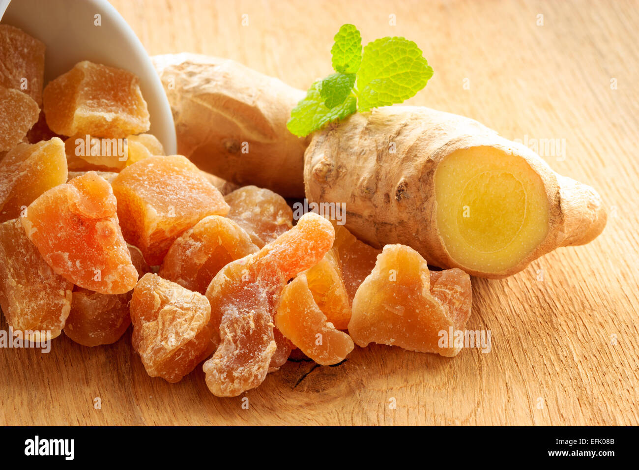 Closeup dried candied crystallized ginger pieces and raw root on wooden ...