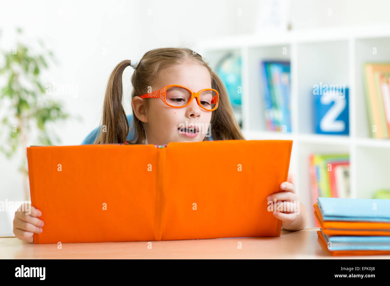 clever kid little girl behind of open book indoor Stock Photo - Alamy