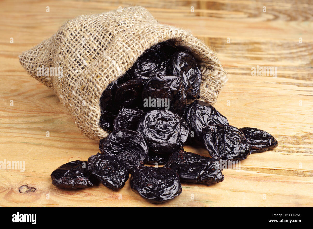 Prunes in small sack on wooden background Stock Photo - Alamy