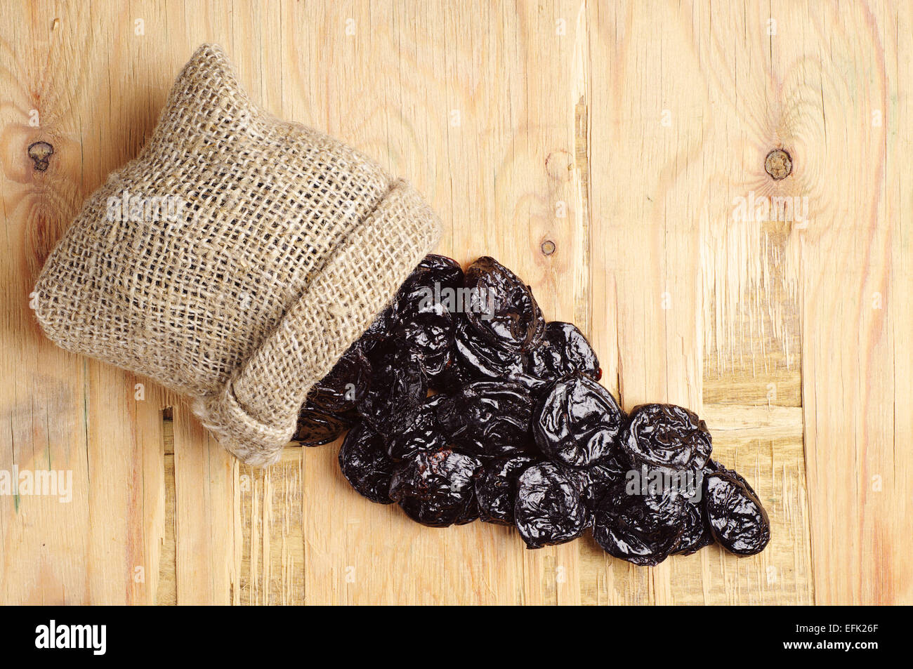 Prunes in small sack on wooden background. Top view Stock Photo - Alamy
