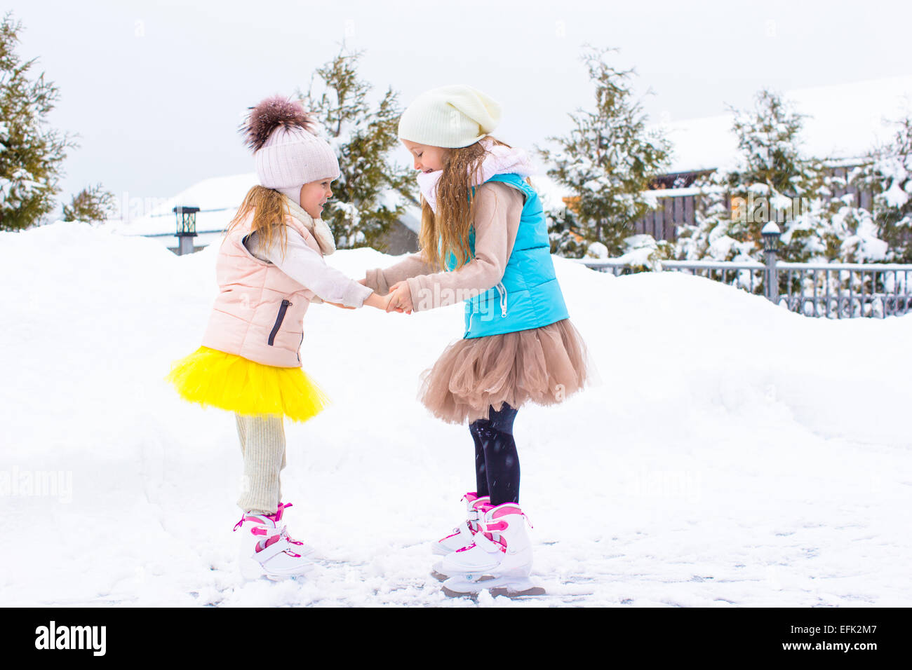 Little girls skating on ice rink outdoors in winter snow day Stock ...