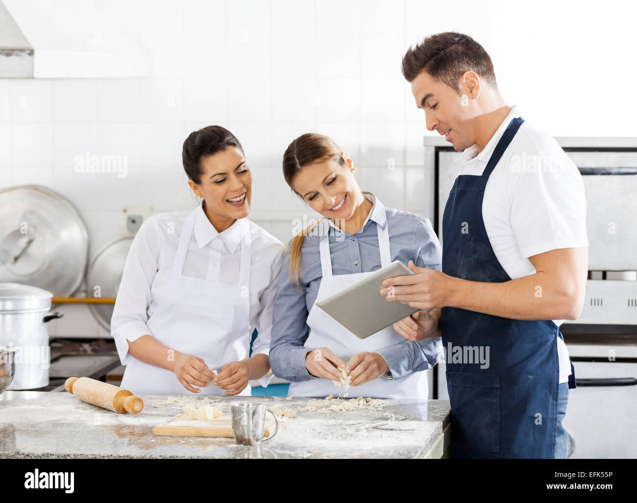 Happy Chefs Checking Recipe On Digital Tablet In Kitchen Stock Photo ...