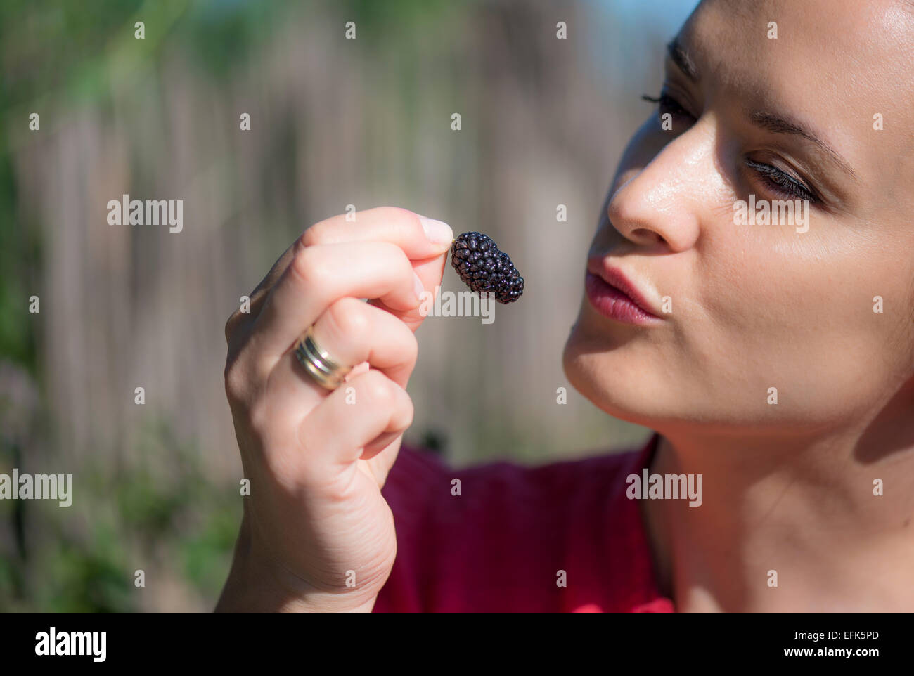 Beautiful woman eating a mulberry Stock Photo - Alamy