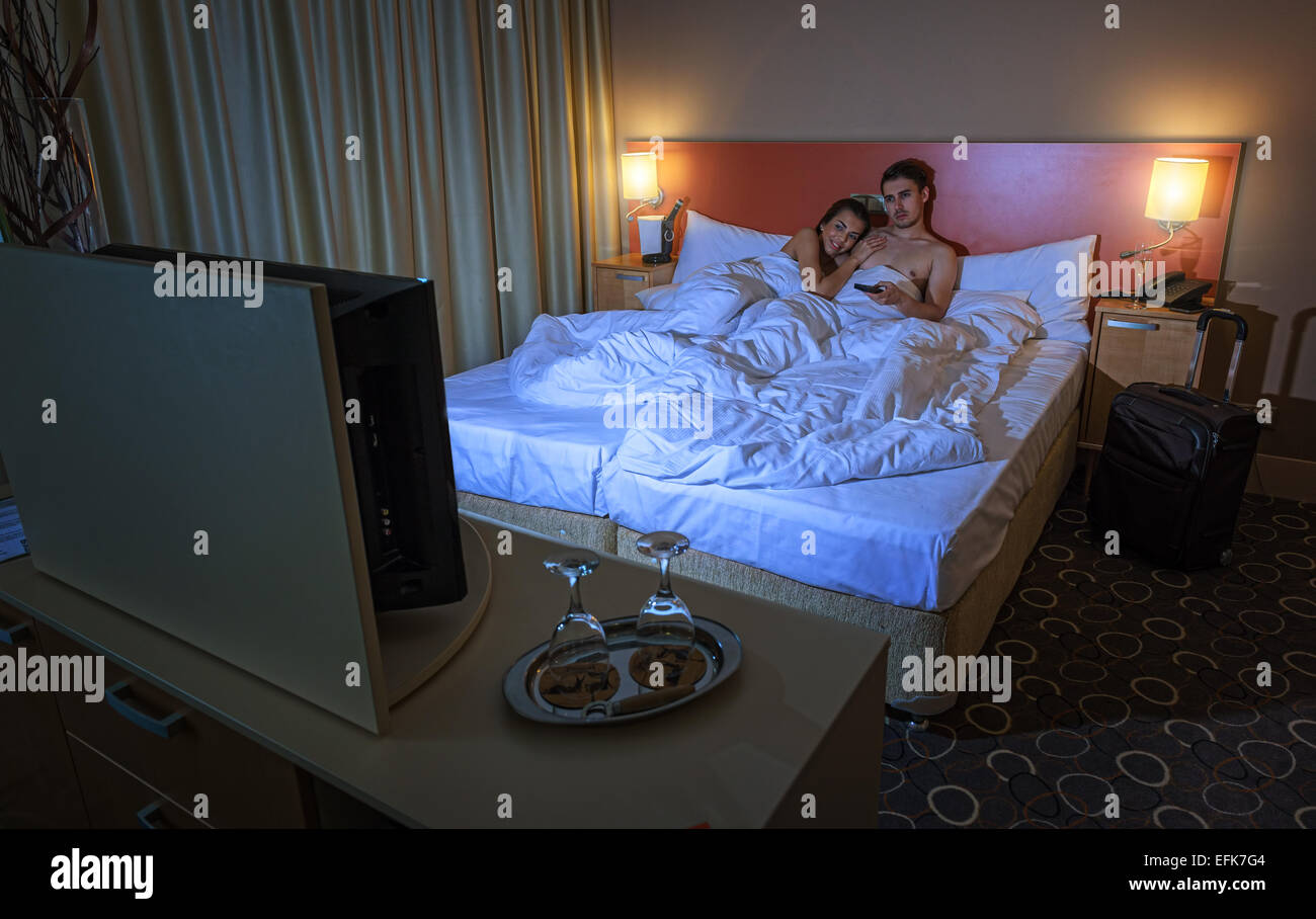 Young couple watching TV in the hotel room at night Stock Photo - Alamy