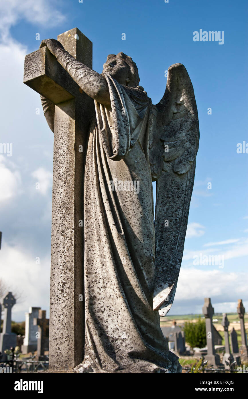Angel statue embracing a cross and celtic graveyard in Ardmore county ...