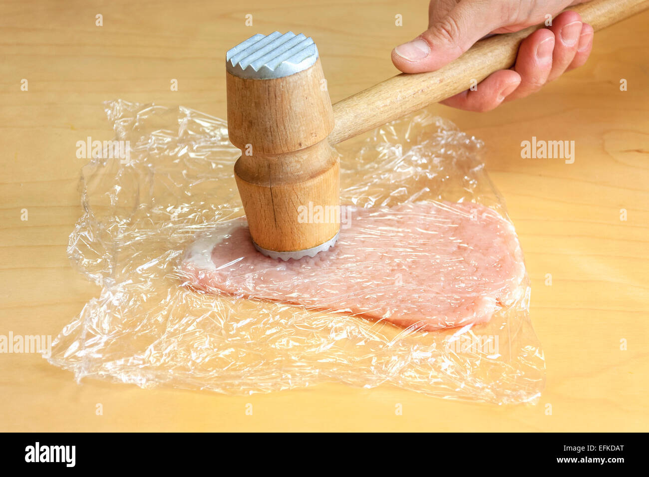 Preparing pork schnitzel - punding foil covered cutlets with meat ...