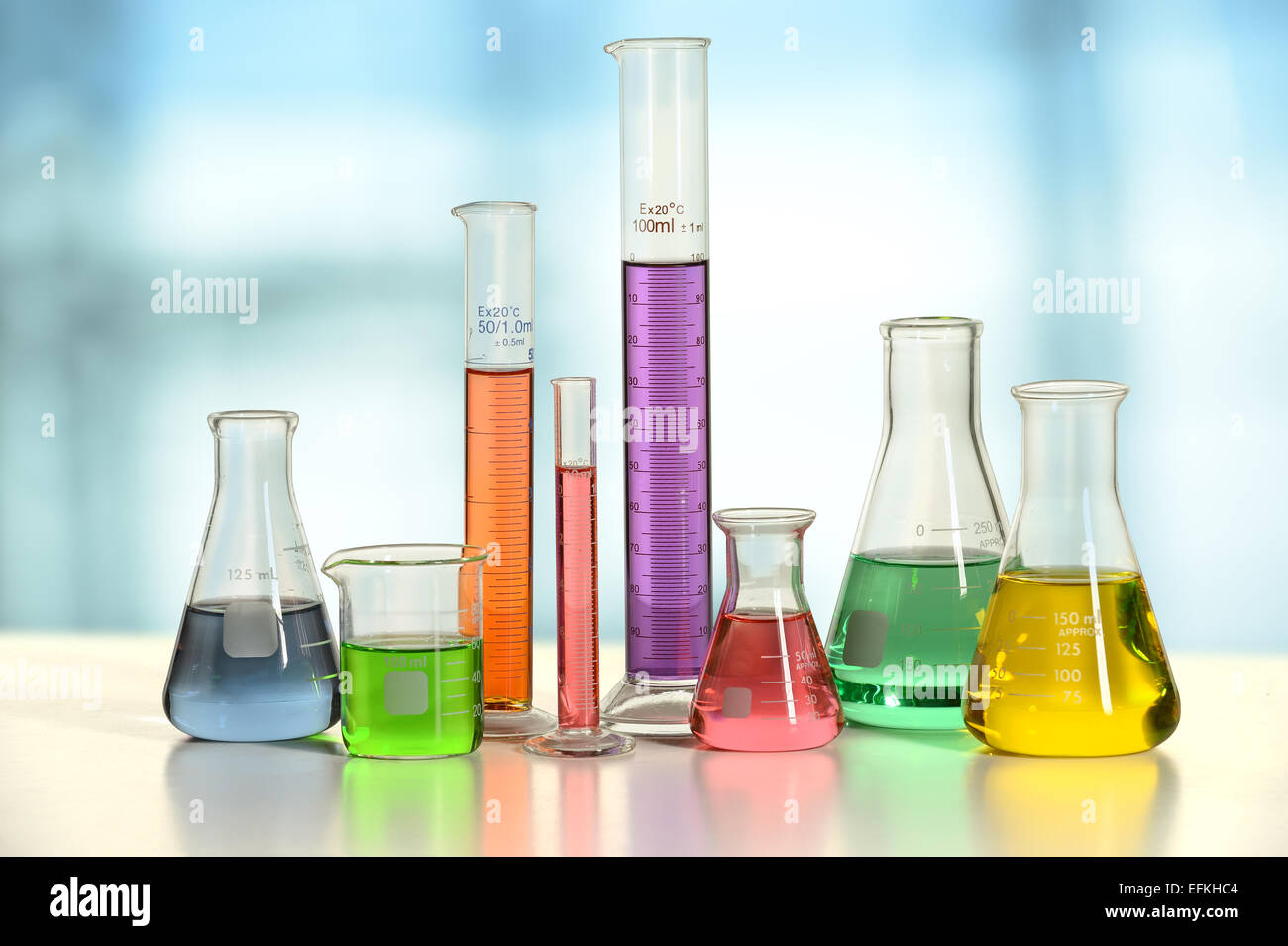 Laboratory glassware with liquids of different colors on white table ...
