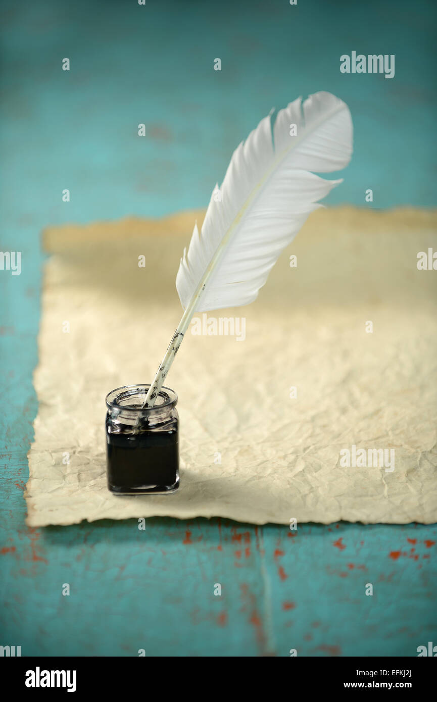 Inkwell and feather with old paper on grunge table Stock Photo - Alamy