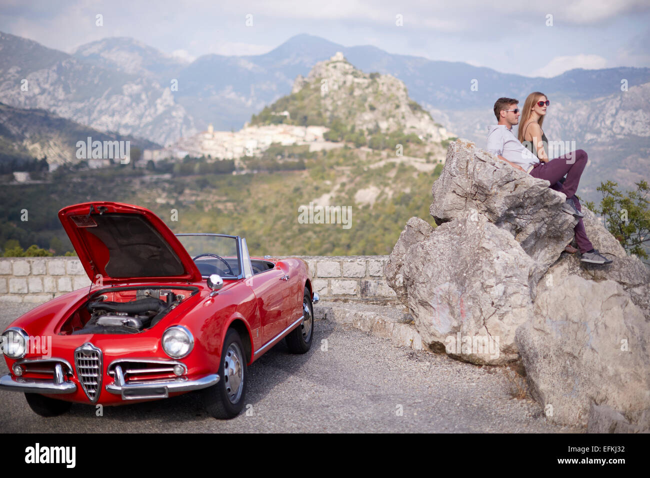 Couple sitting waiting for rescue with a broken down classic car in the ...