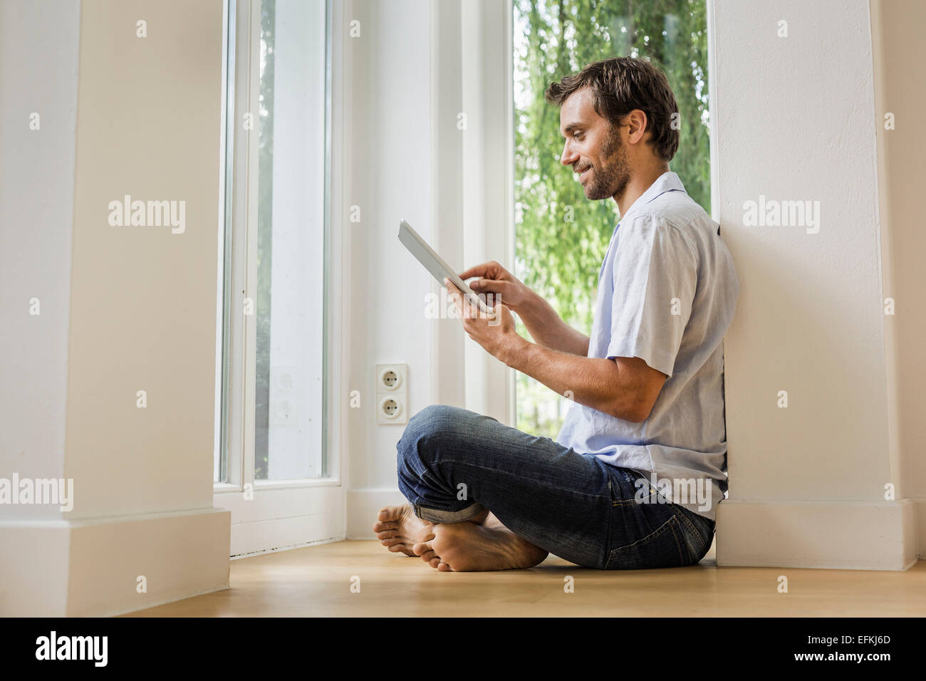 Mid adult man using touchscreen on digital tablet in sitting room Stock ...