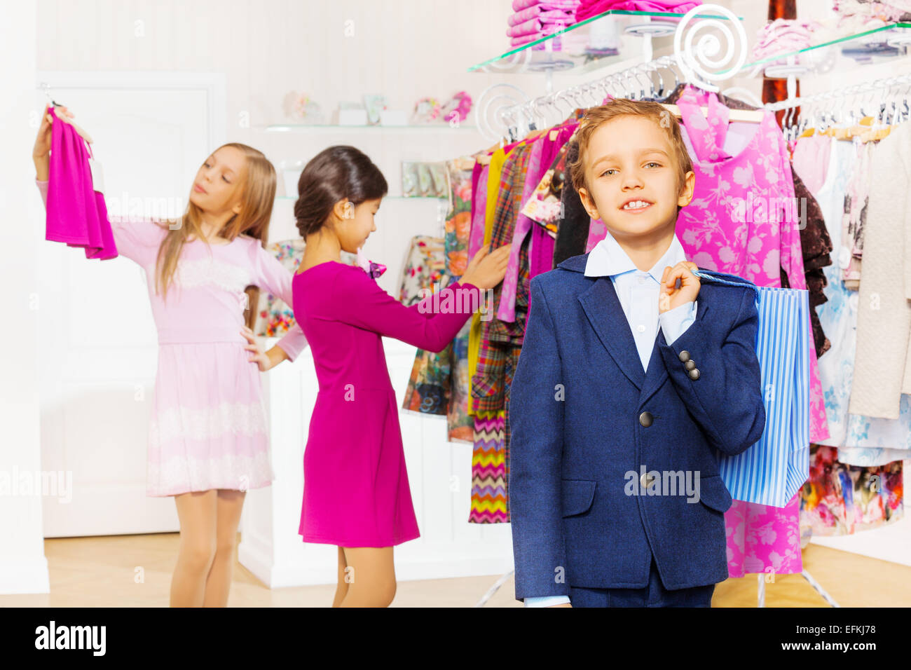 One boy with shopping bag and girls choose clothes Stock Photo - Alamy