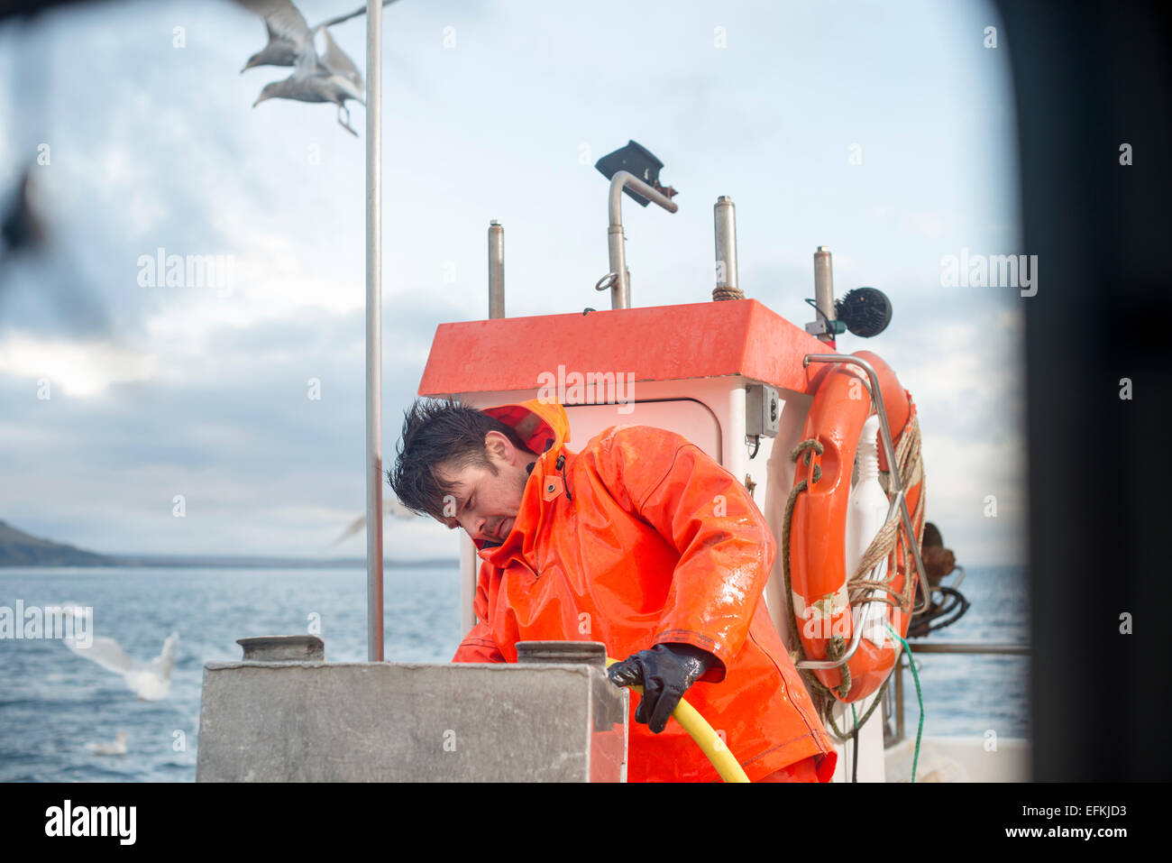 Fisherman cleaning fishing boat Stock Photo - Alamy
