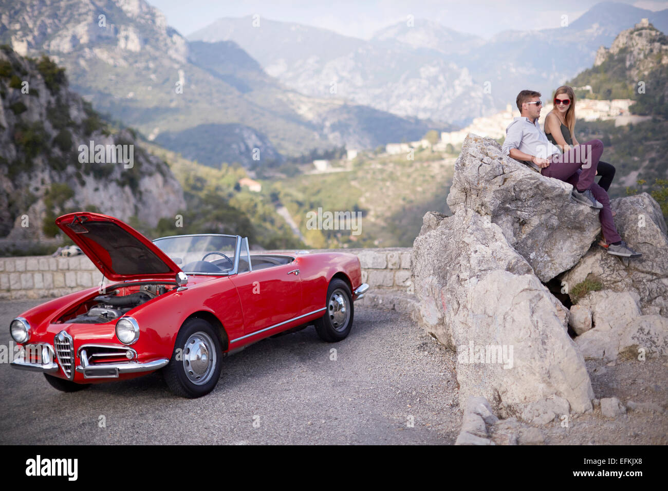 Couple sitting waiting for rescue with a broken down classic car in the ...