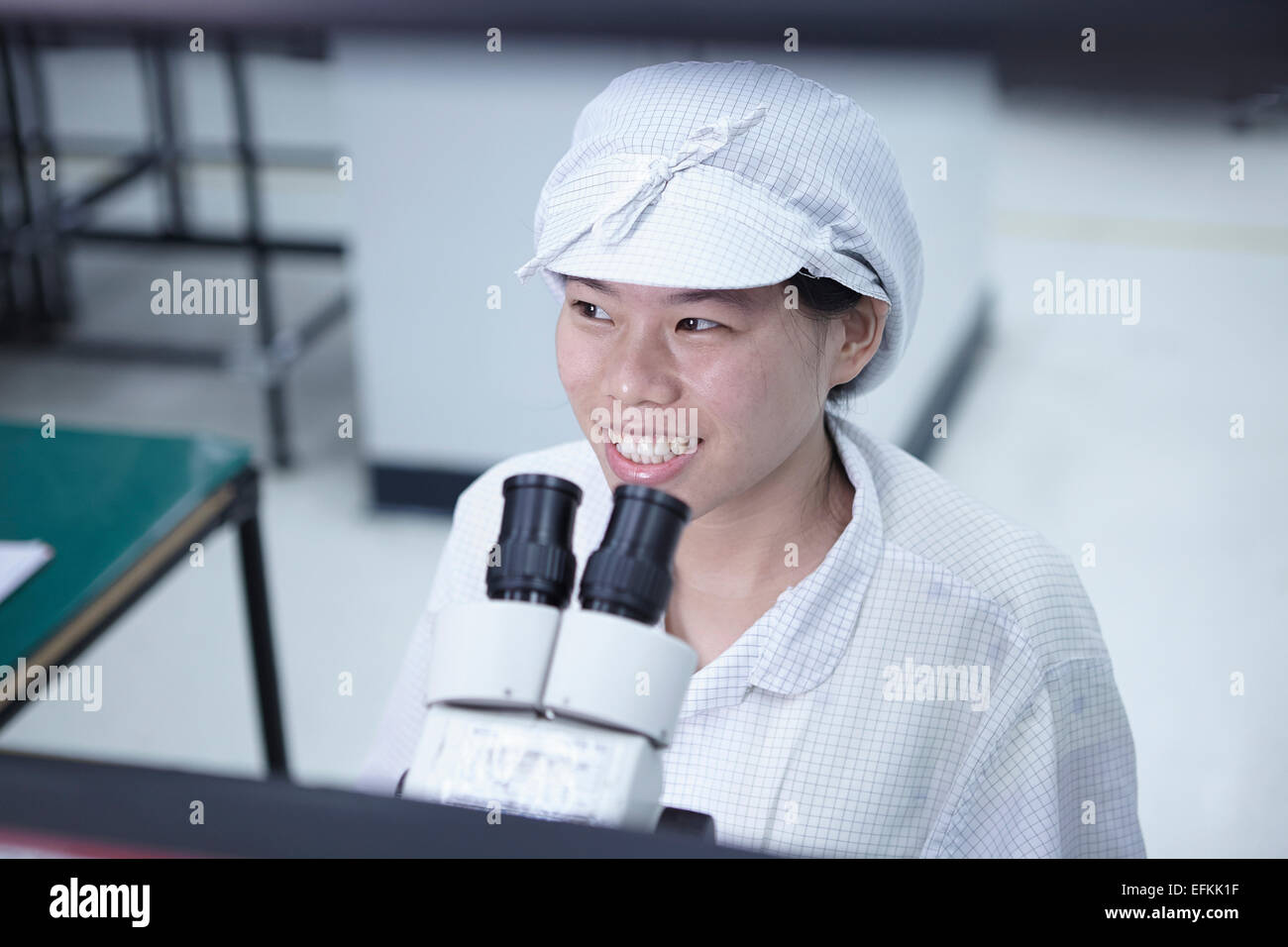 Worker using microscope in factory that specialises in creating ...