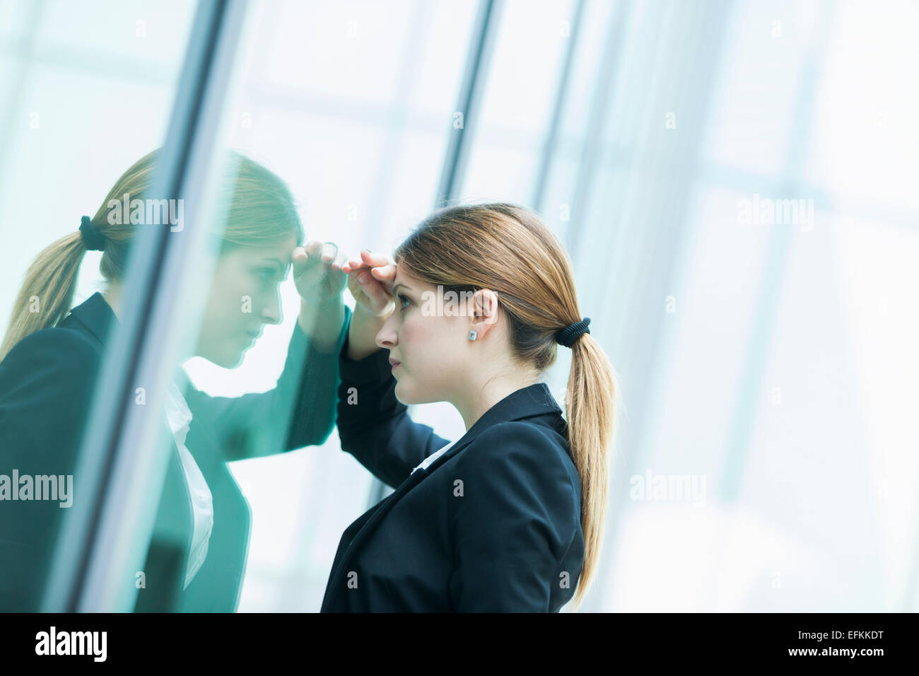 Businesswoman peering through glass window Stock Photo - Alamy