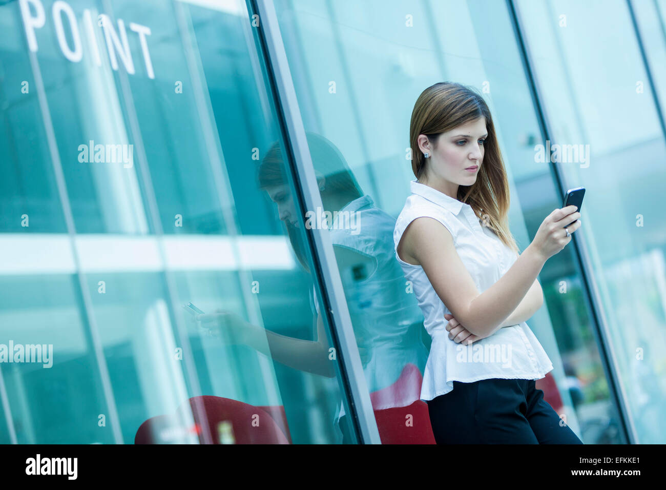 Woman using smartphone against glass window Stock Photo - Alamy