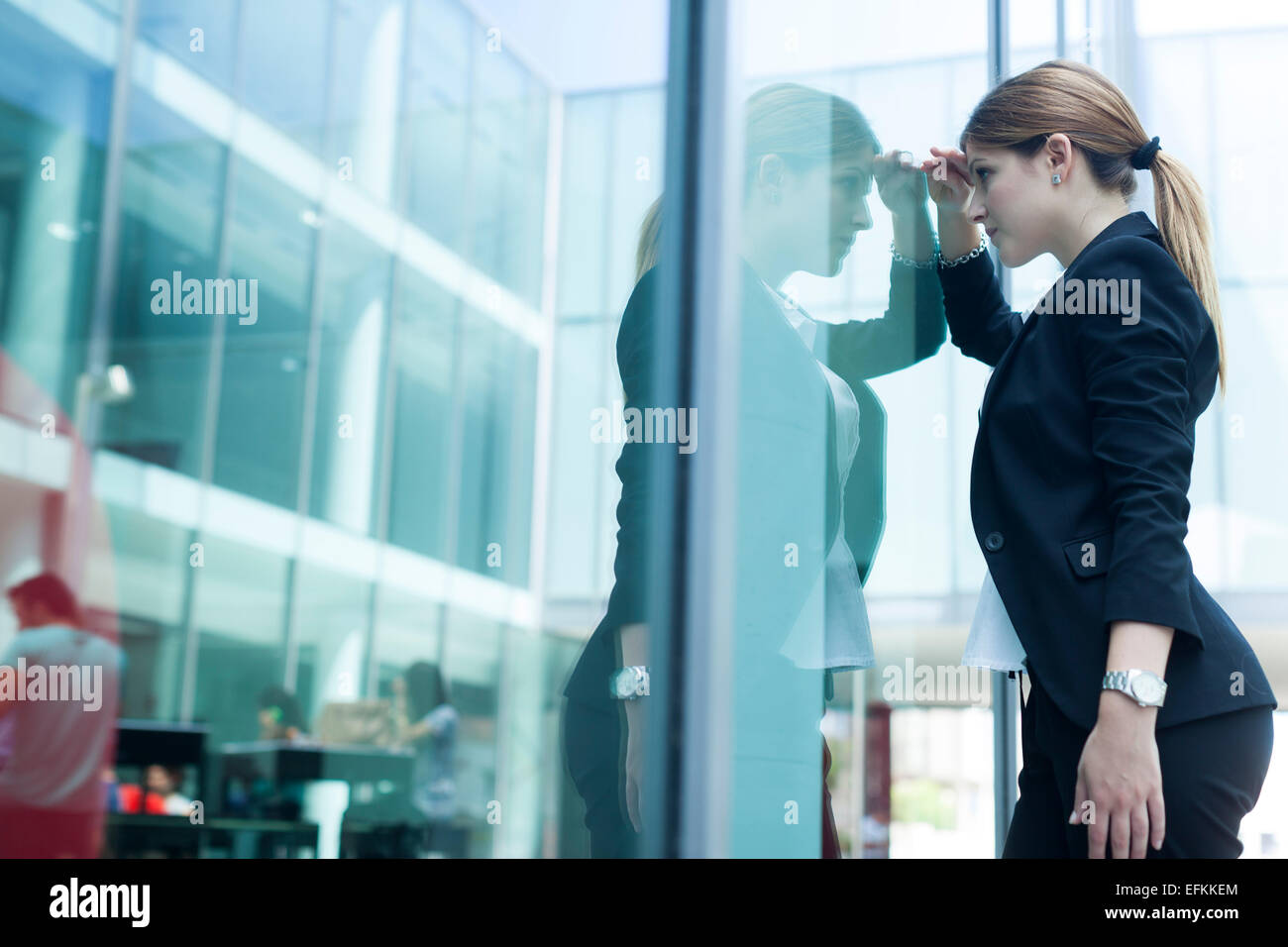 Businesswoman peering through glass window Stock Photo - Alamy