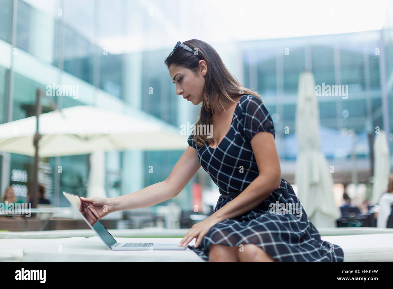 Woman using laptop by outdoor cafe Stock Photo - Alamy