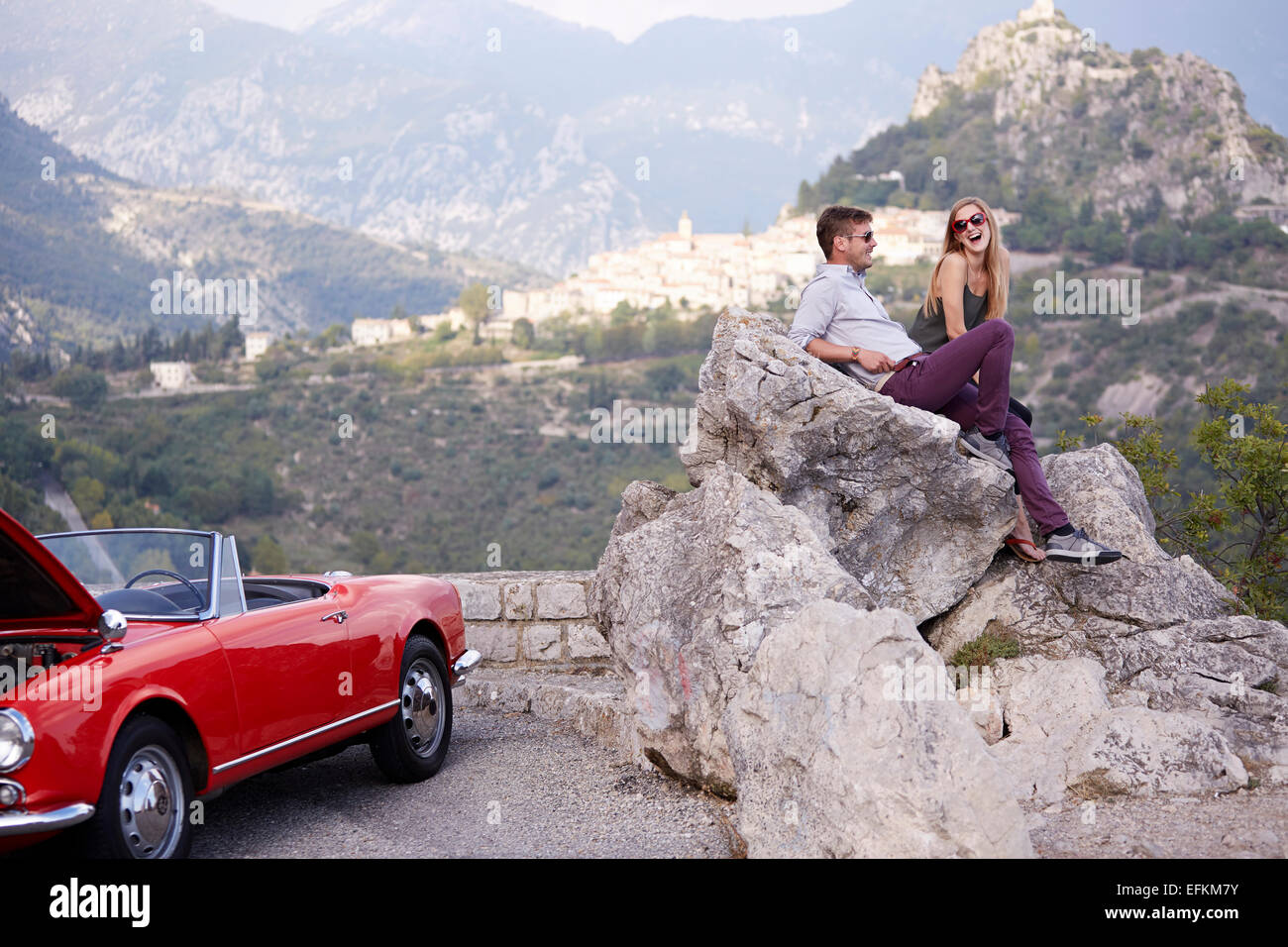 Couple sitting waiting for rescue with a broken down classic car in the ...