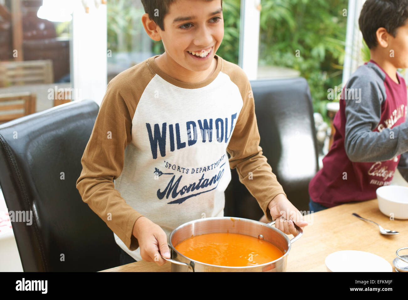Boys at kitchen table holding pan of tomato soup Stock Photo - Alamy