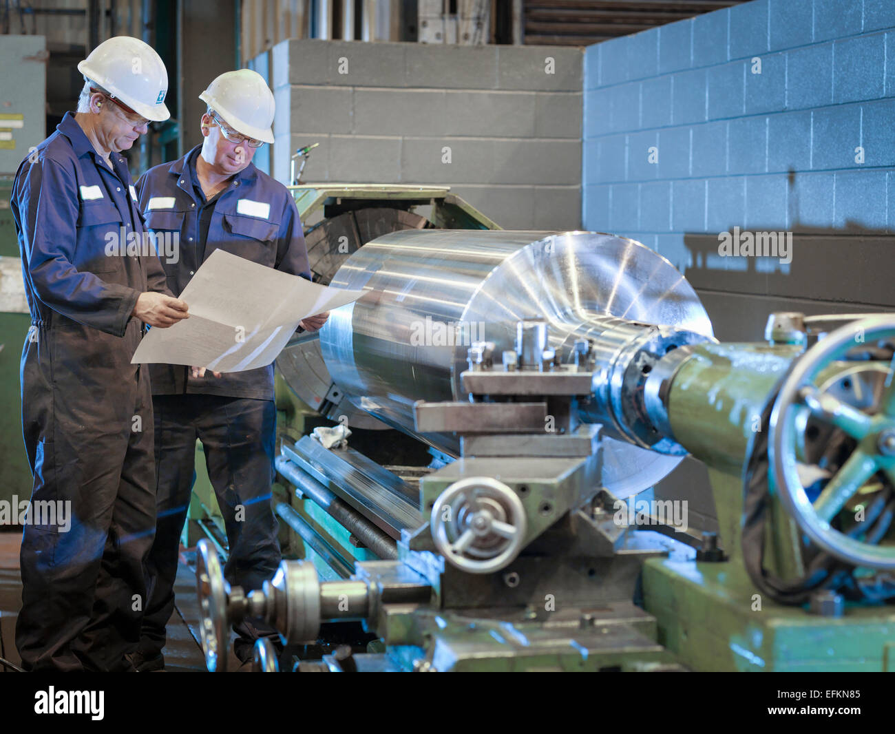 Engineers working with drawings on lathe Stock Photo - Alamy