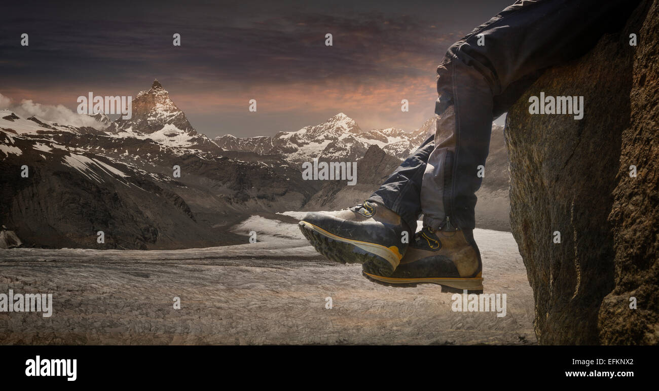 Legs of male climber dangling over rock edge, Zermatt, Matterhorn ...