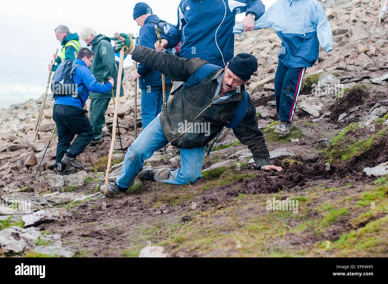 A man falls as he tries to descend the loose rocks of Croagh Patrick ...