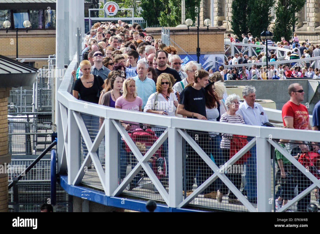 Thousands of people crammed together walk along a narrow pedestrian ...