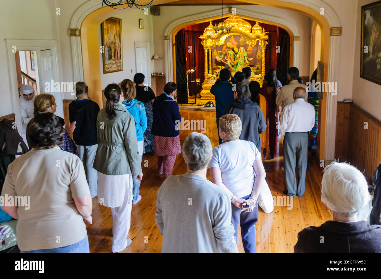 Hare Krishna devotees stand to pray and celebrate in front of an altar ...