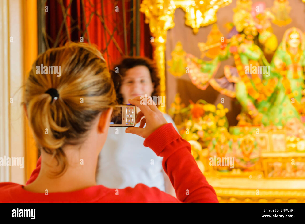 A woman has her photograph taken in front of a golden Hare Krishna ...