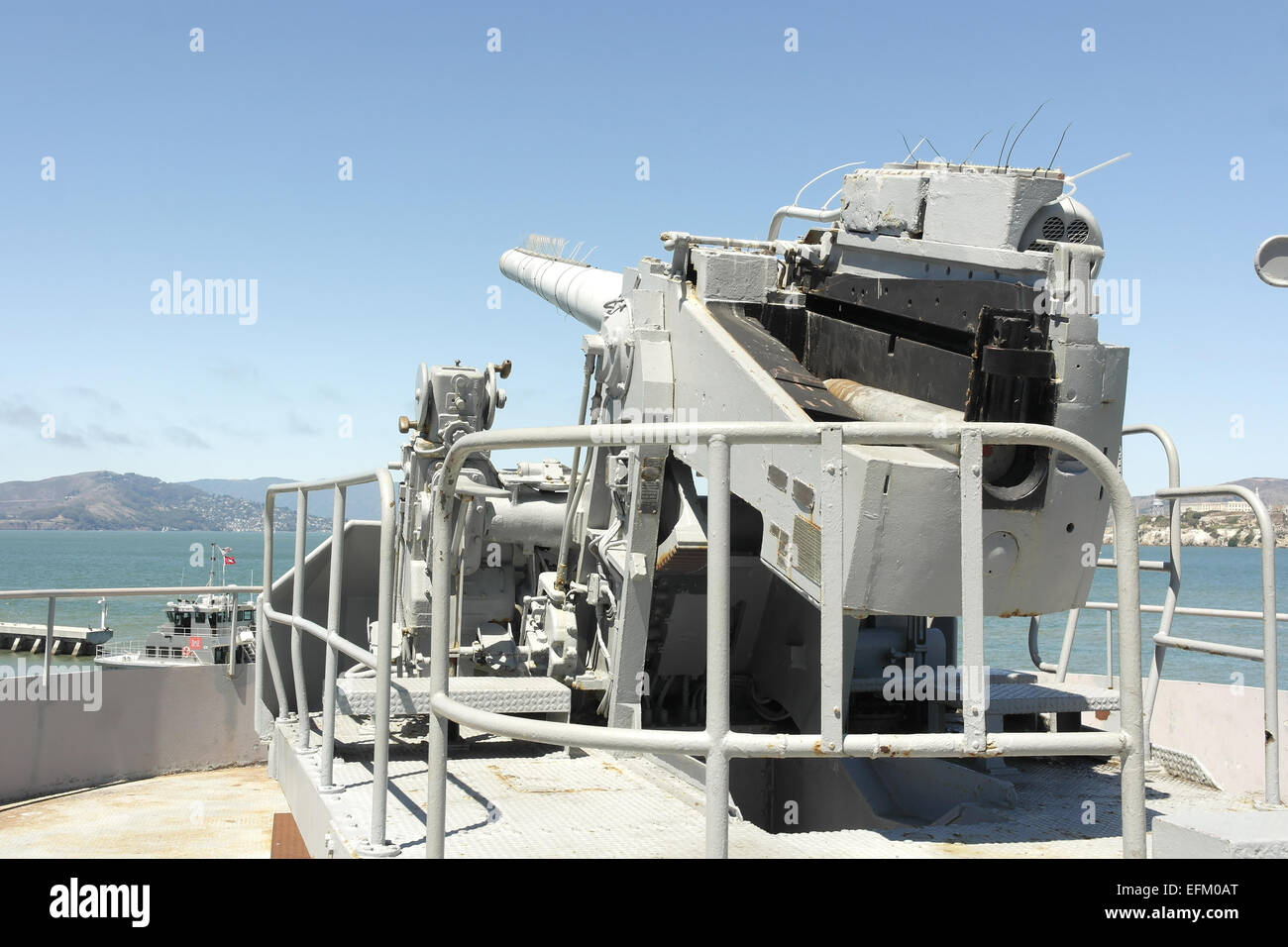 Blue sky view stem mounted 5-inch deck gun pointing towards bay waters ...