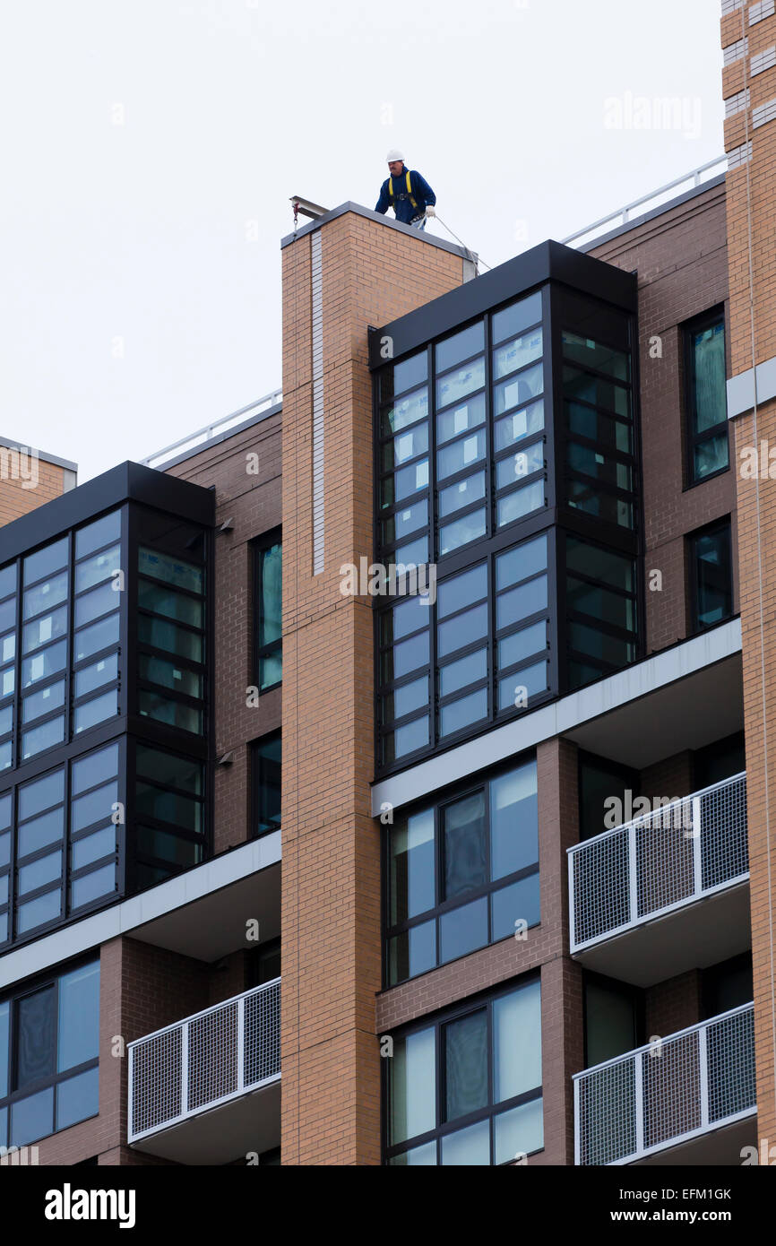 Man working on ledge atop a highrise building - USA Stock Photo - Alamy