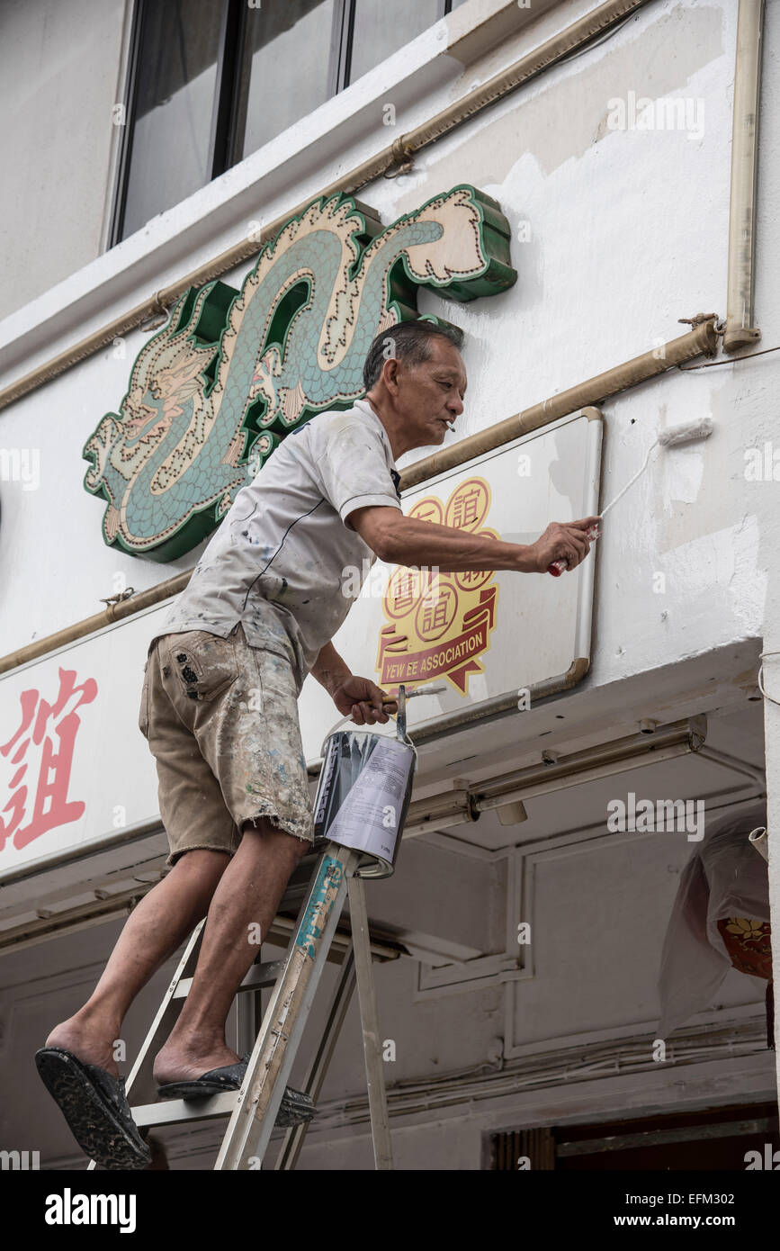 Elderly man painting sign in community association premises in ...