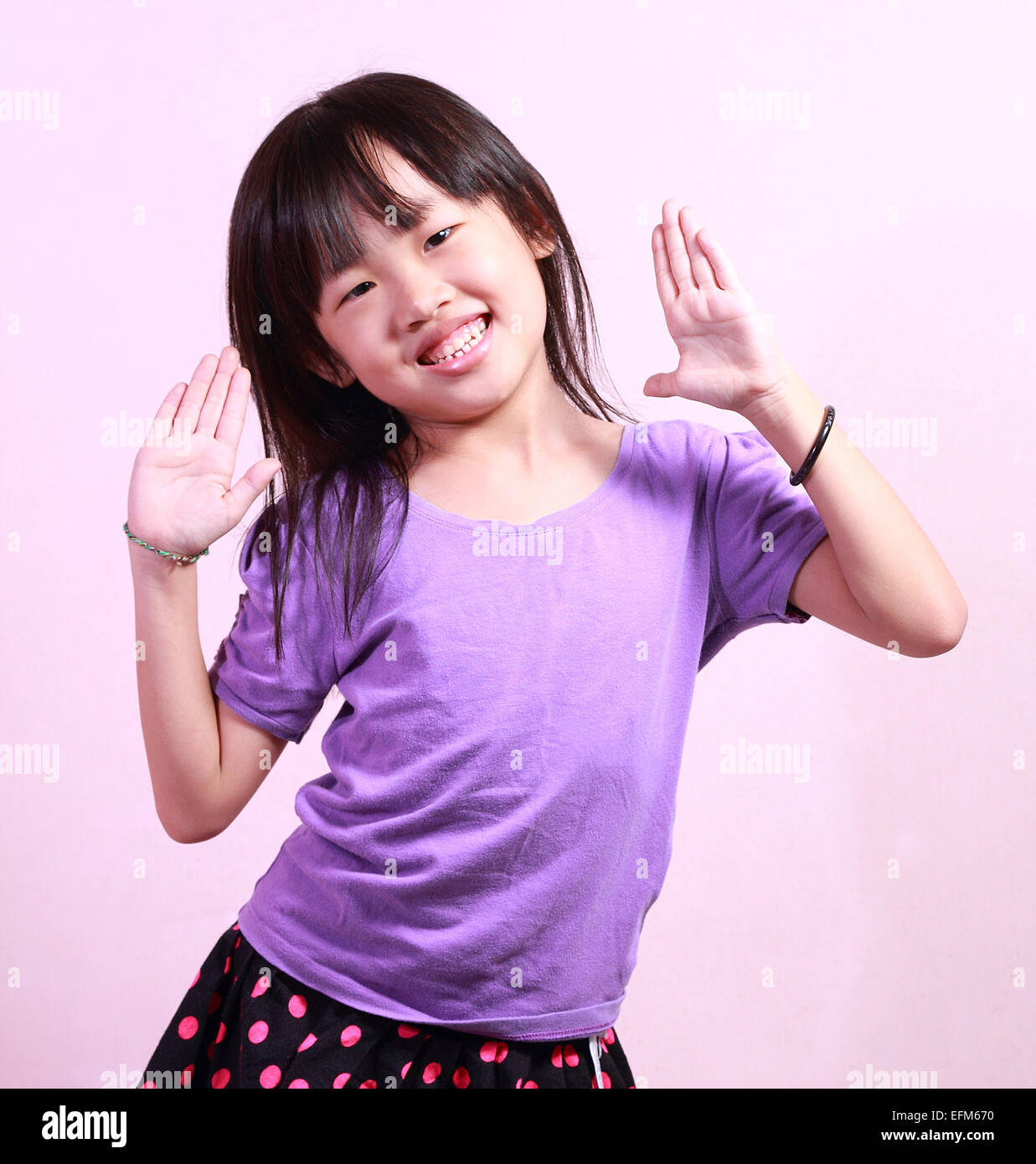 A cute little girl raising her hands and smilling Stock Photo - Alamy