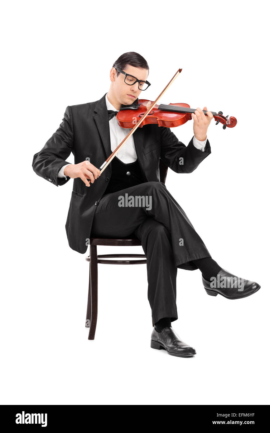 Studio shot of a classical musician playing violin seated on chair ...