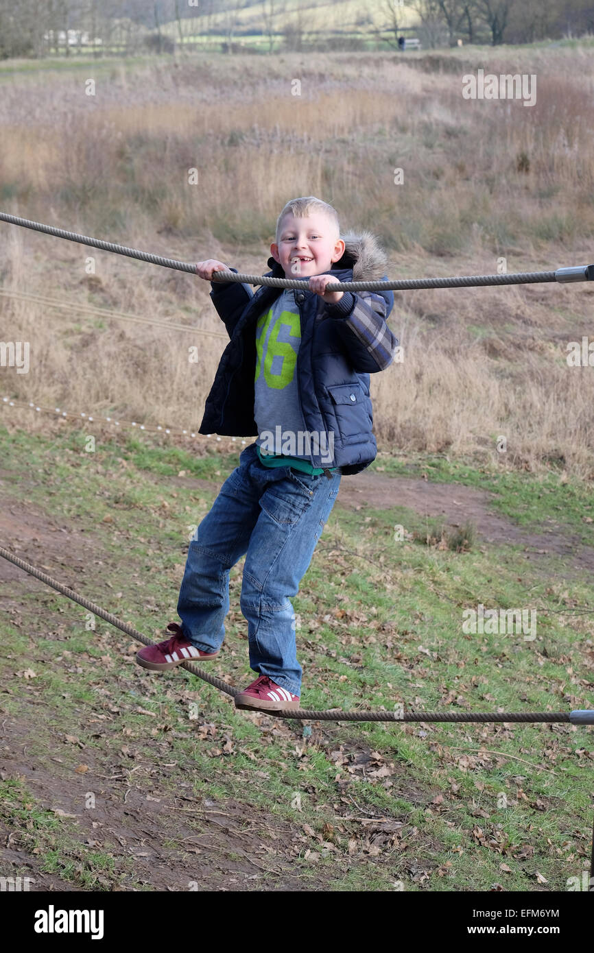 Boy balancing on rope bridge on adventure playground Stock Photo - Alamy