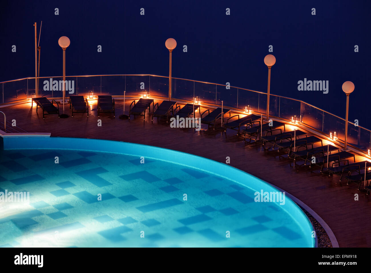 Sun loungers on the poolside in a night scene Stock Photo - Alamy
