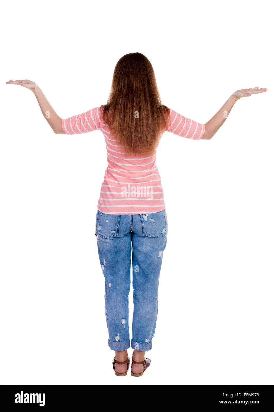 Back view of Beautiful woman in jeans looking at wall and Holds hand up ...