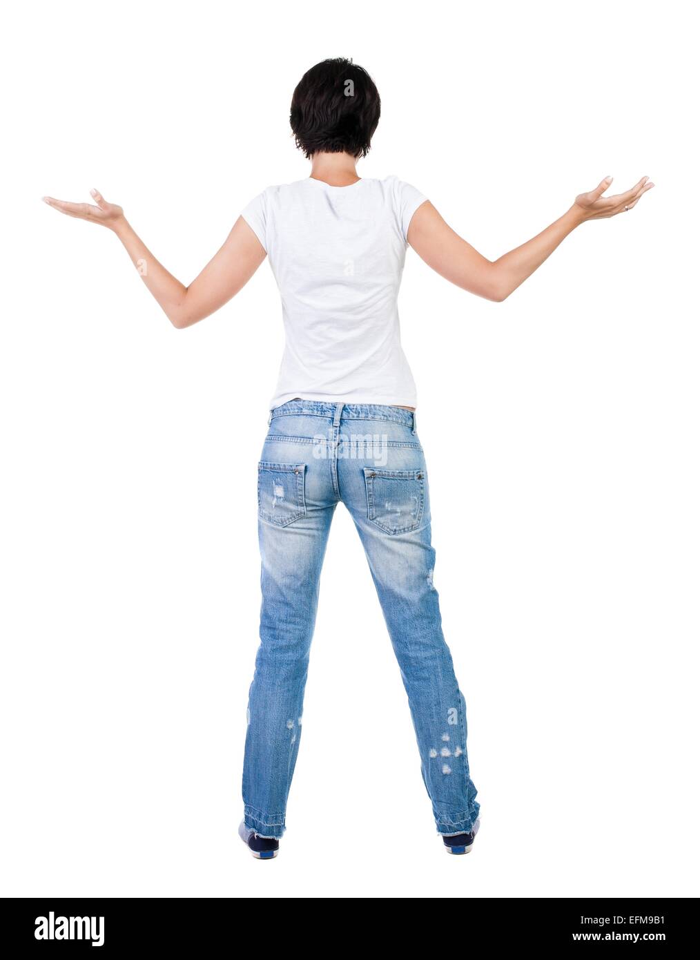 Back view of Beautiful woman in jeans looking at wall and Holds hand up ...