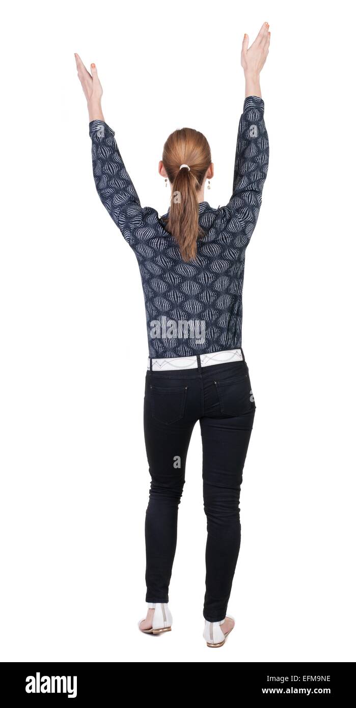 Back view of Beautiful woman in jeans looking at wall and Holds hand up ...