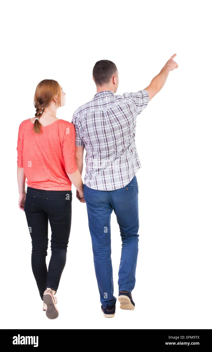 Back view of walking young couple (man and woman) pointing. Rear view ...