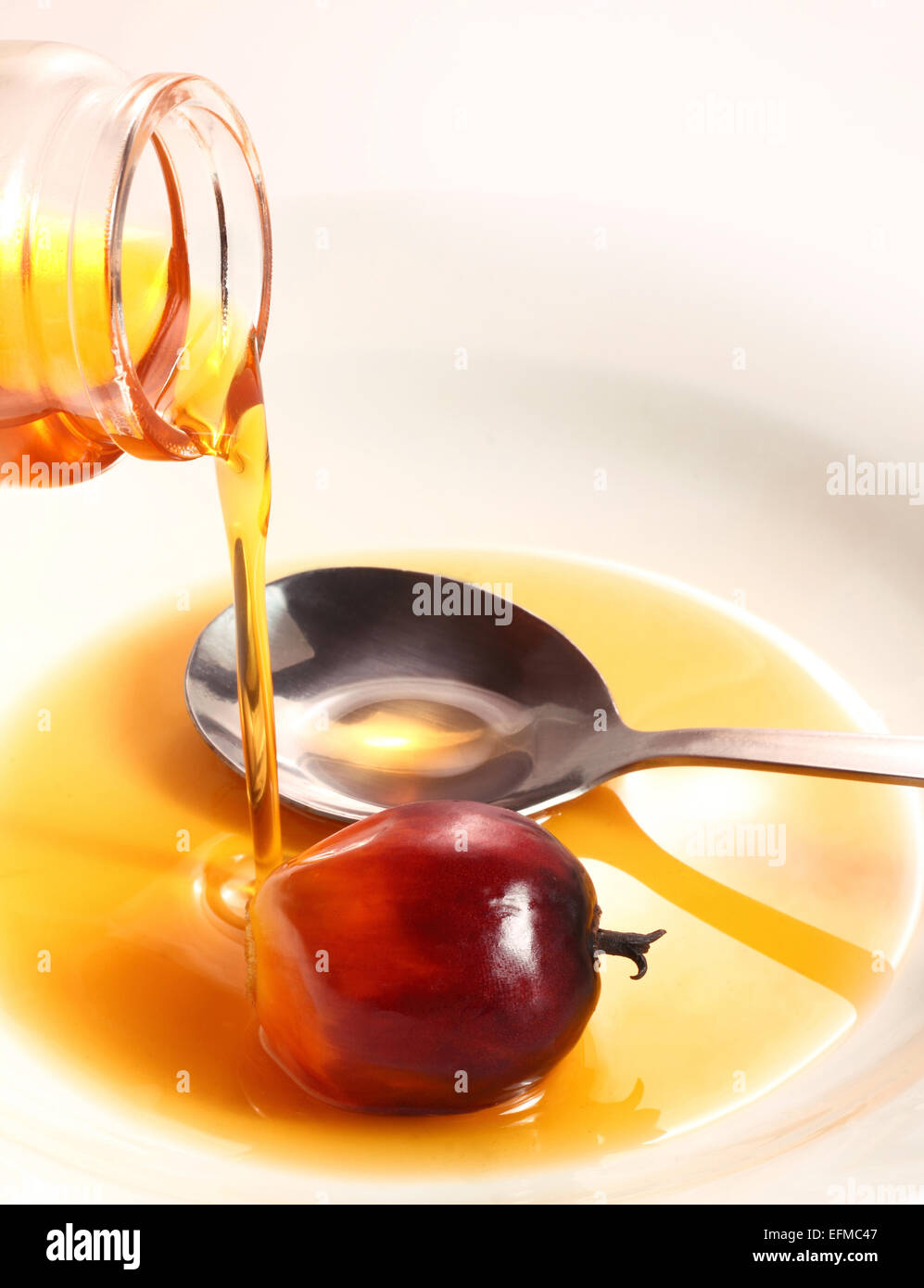 A bottle of palm cooking oil pouring in a white plate Stock Photo - Alamy
