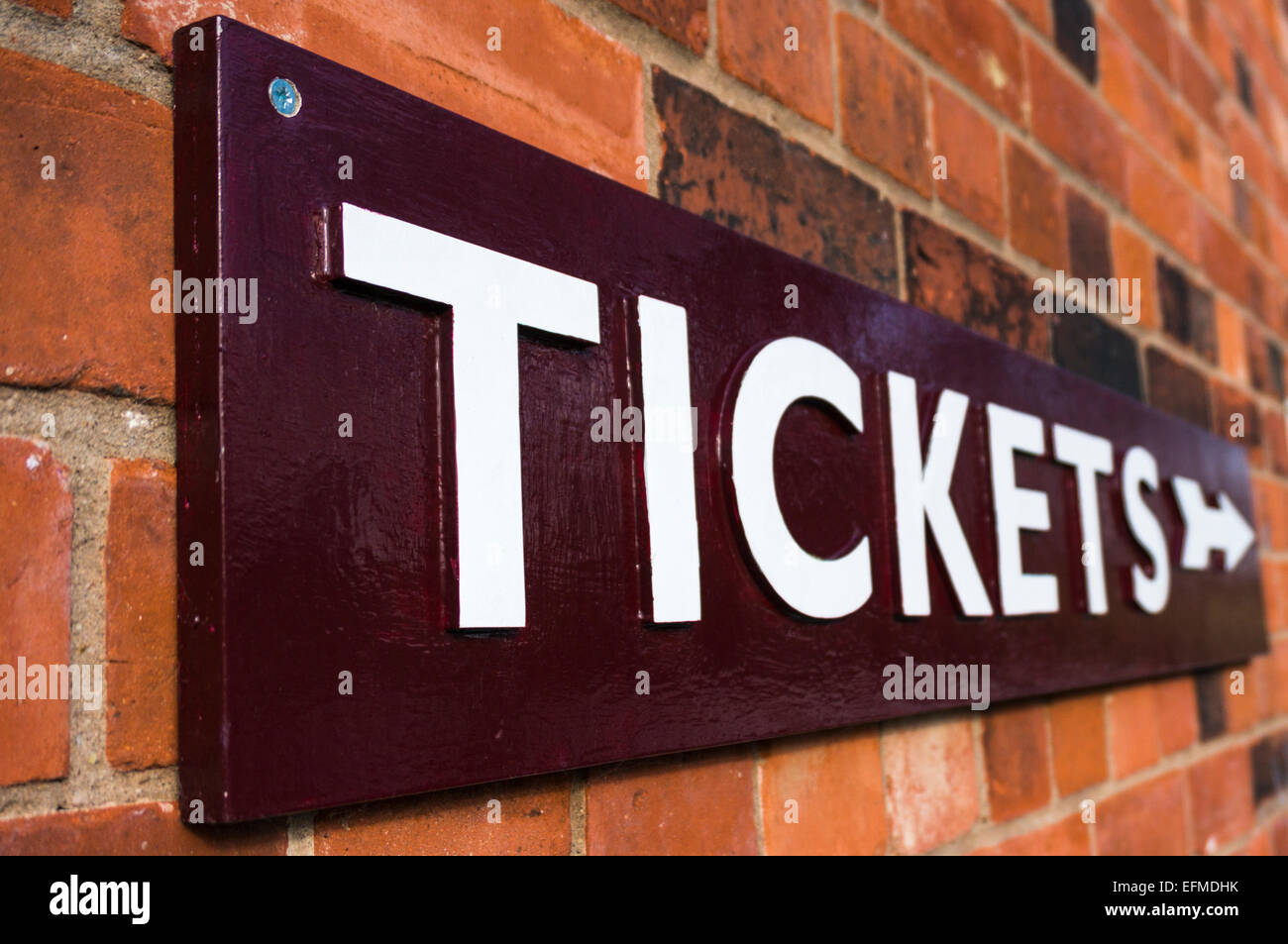 Close up of a large Tickets sign with arrow mounted on a brick wall ...