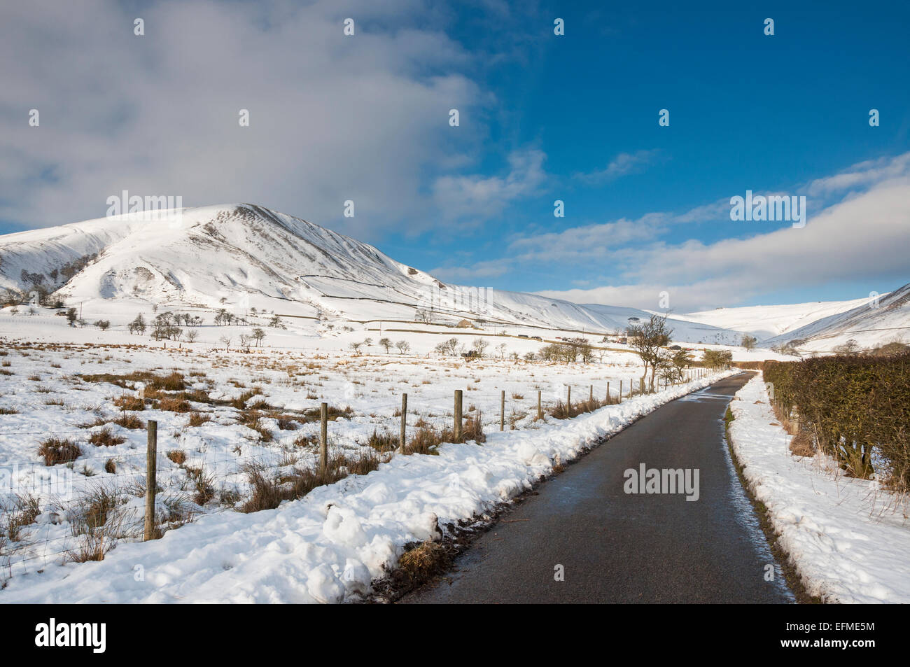 An English country lane in a snowy winter landscape in the Peak ...